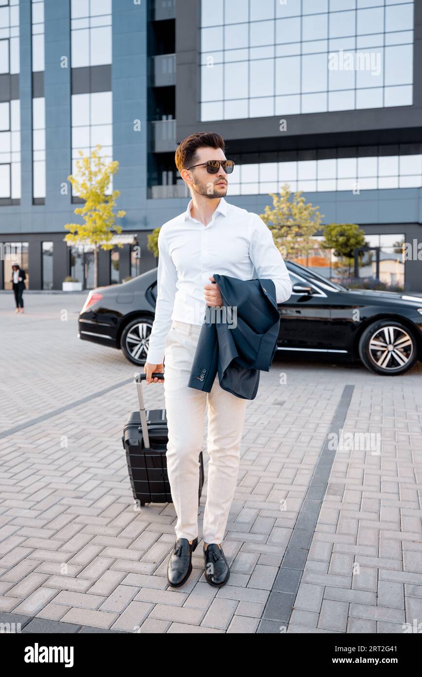 Elegant businessman walks with a suitcase outdoors Stock Photo - Alamy