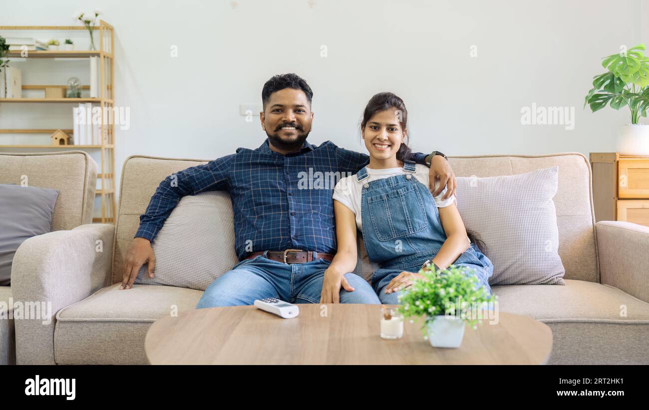 Happy married indian couple watching television and hugging, sitting on ...