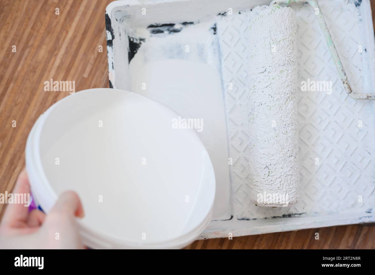 A professional interior construction worker pours white paint into a ...