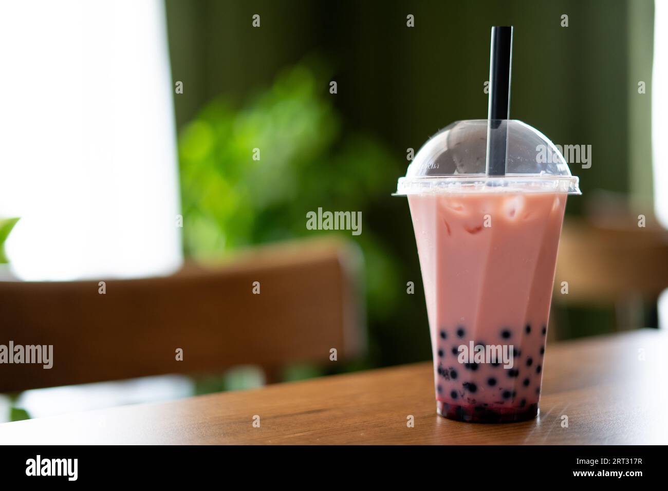 Milk bubble tea in takeaway glass on table in cafe blurred background ...