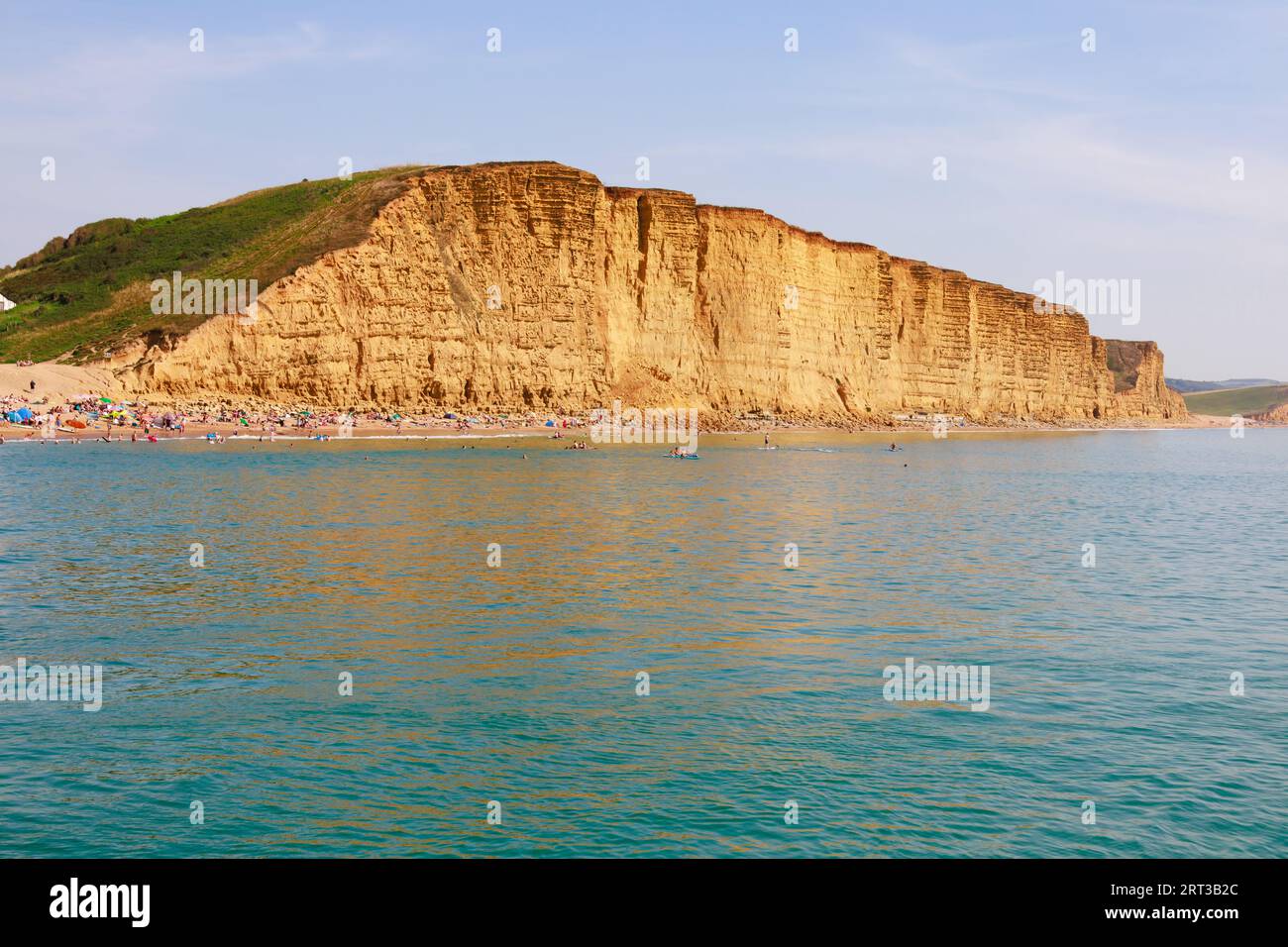 The golden cliffs of West Bay with sunbathers and swimmers after recent ...