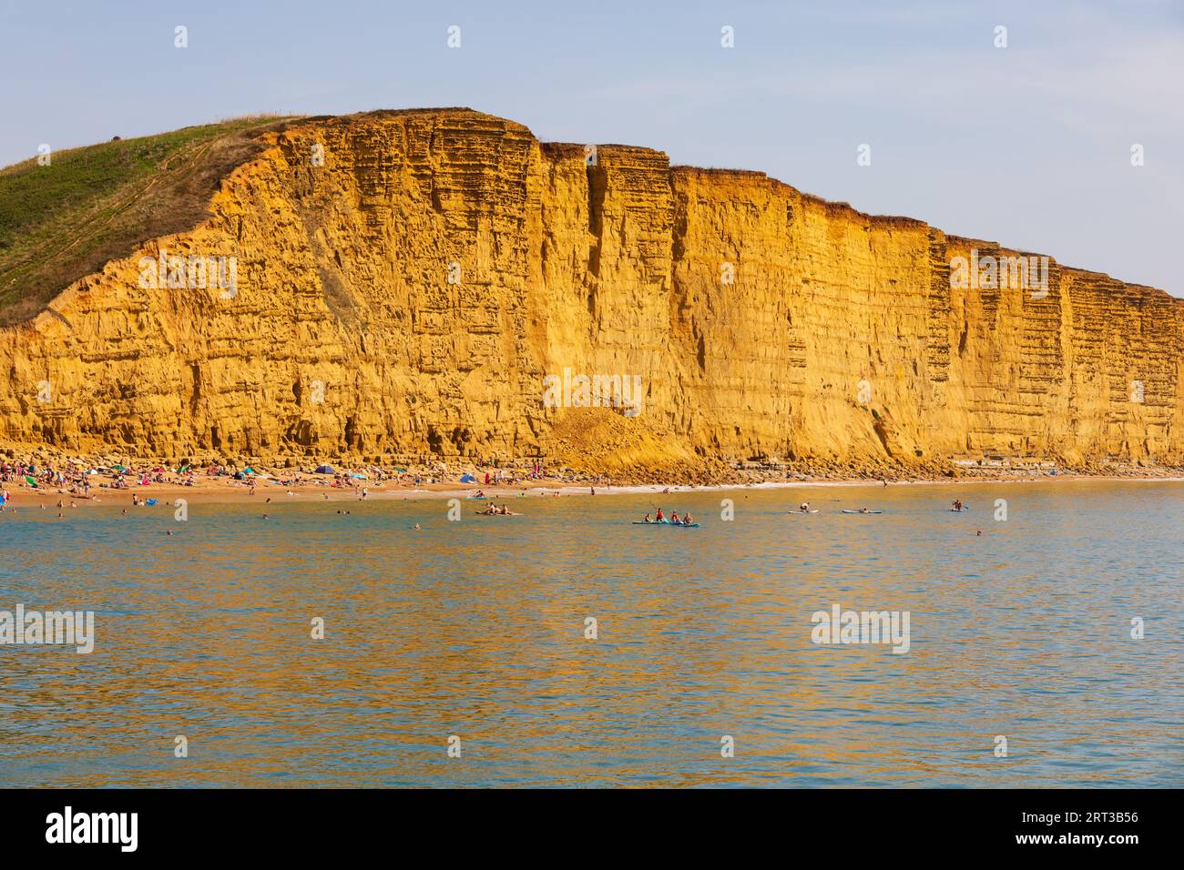 The golden cliffs of West Bay with sunbathers and swimmers after recent ...