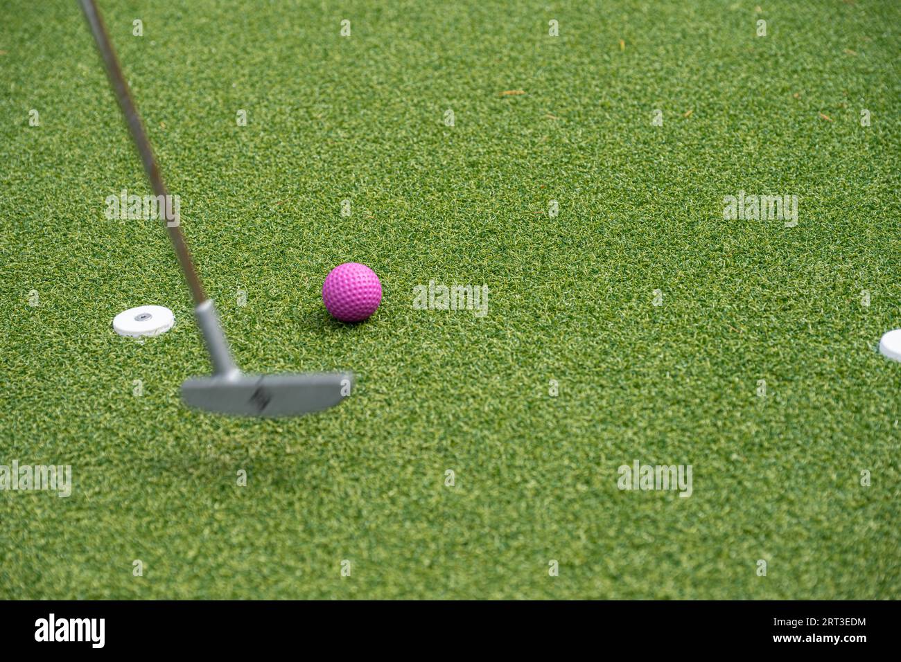 Miniature golf putter by blue ball and hole Stock Photo - Alamy