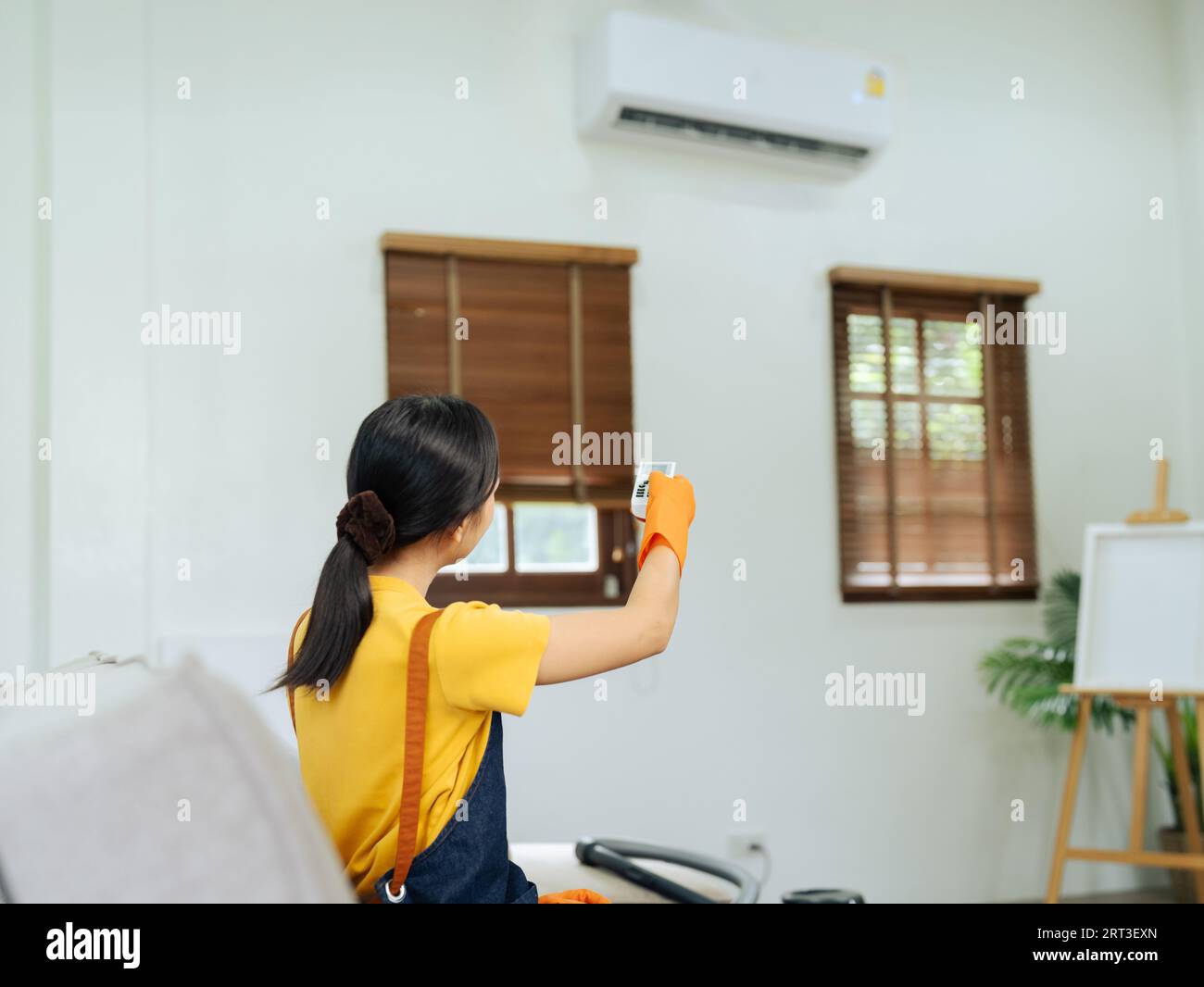 Young woman cooling down after finish housework by air conditioner at ...