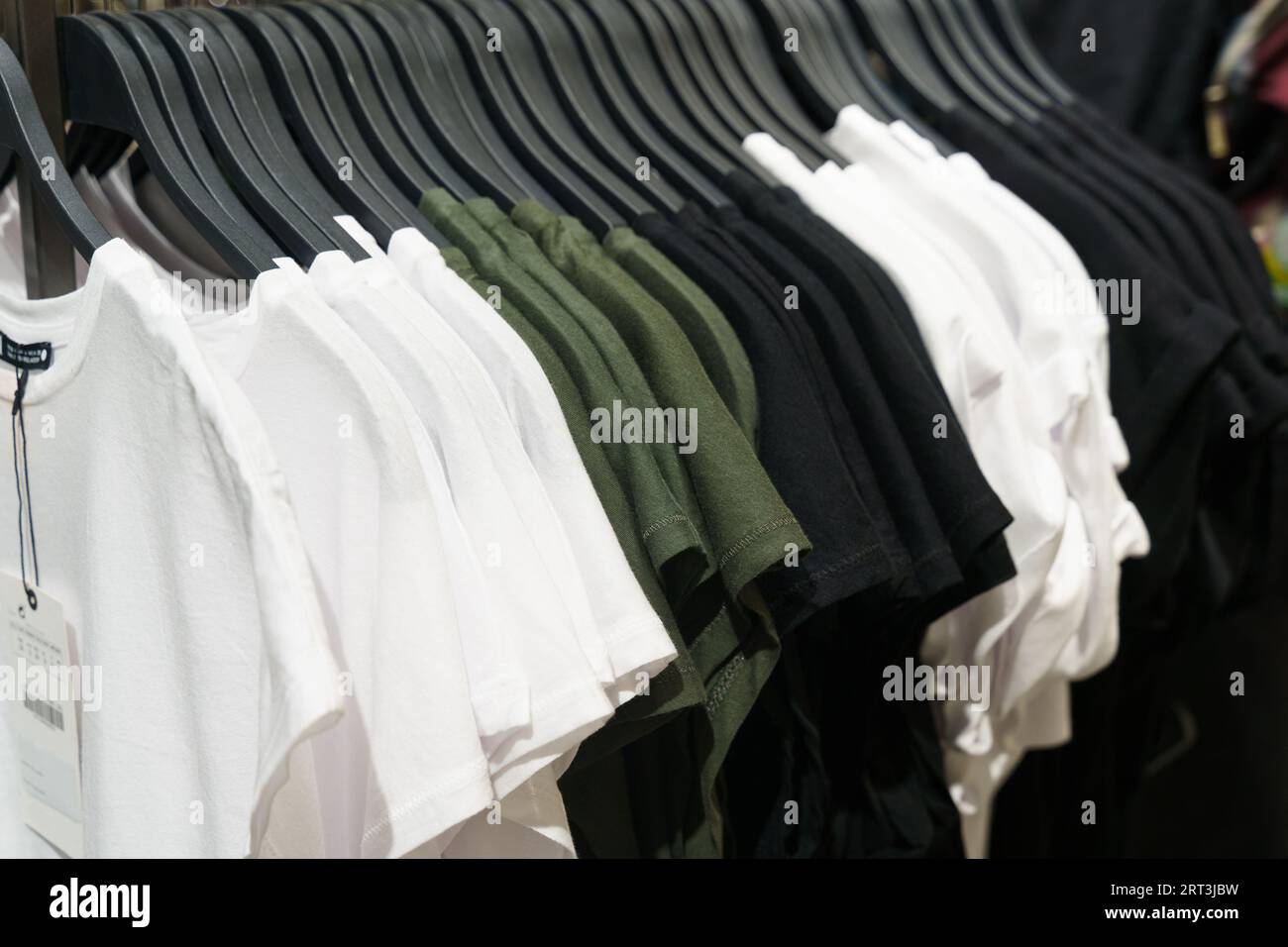A collection of pastel-colored T-shirts hanging on a clothes rack on a ...