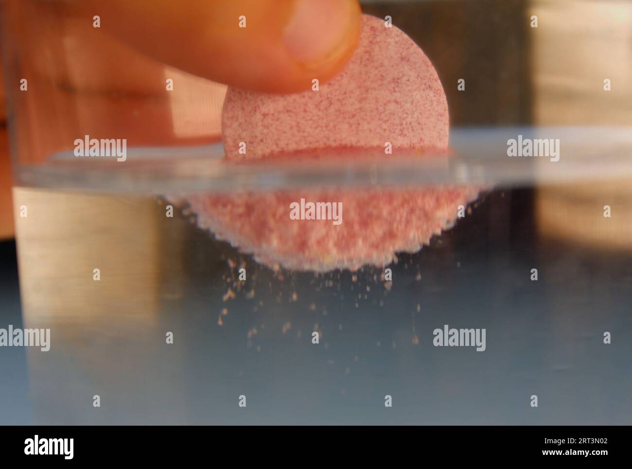 A photo of a pink electrolyte tablet dissolving in a glass of water ...