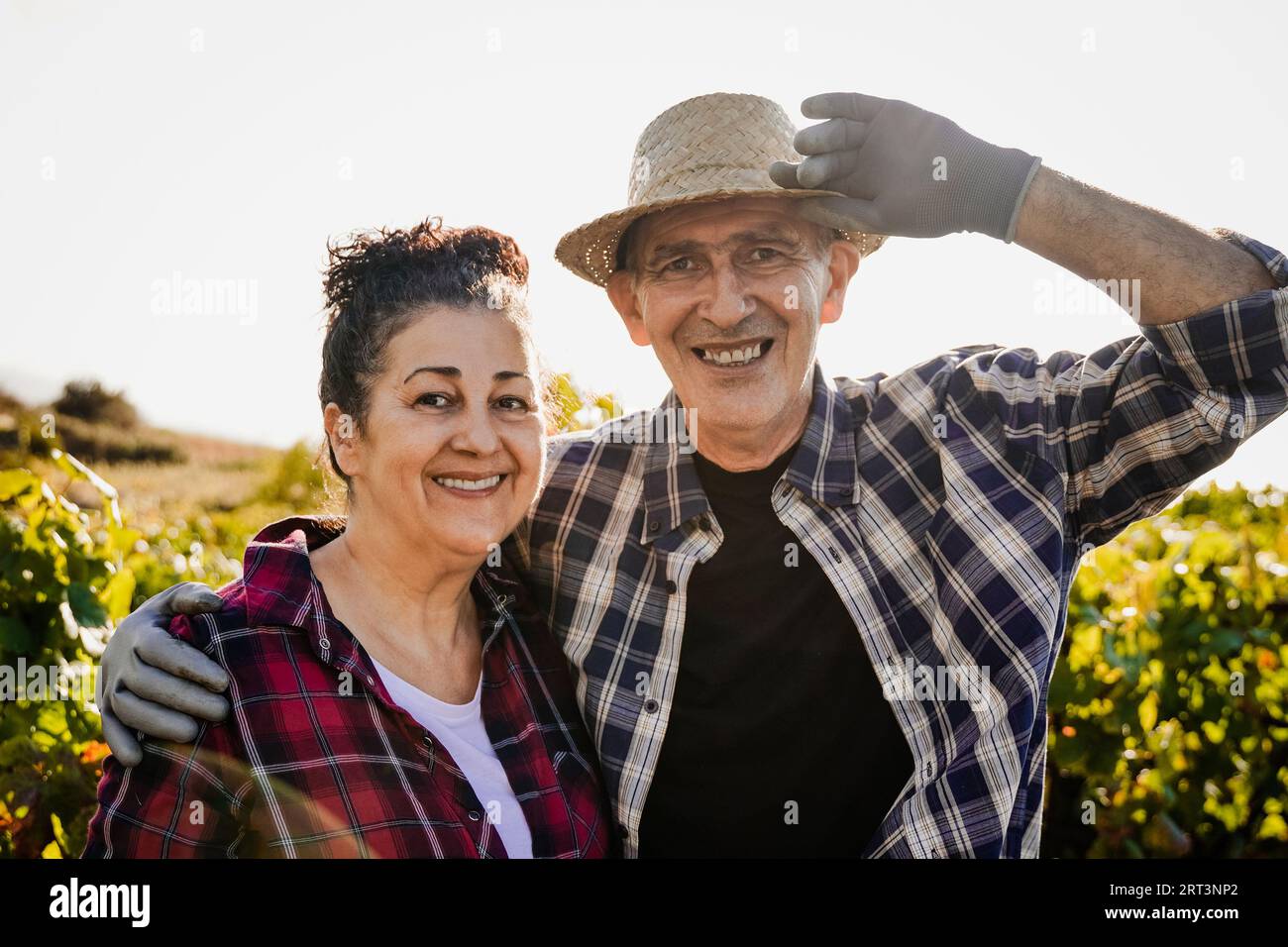 Happy senior farmer couple looking at camera with rural field farm in ...