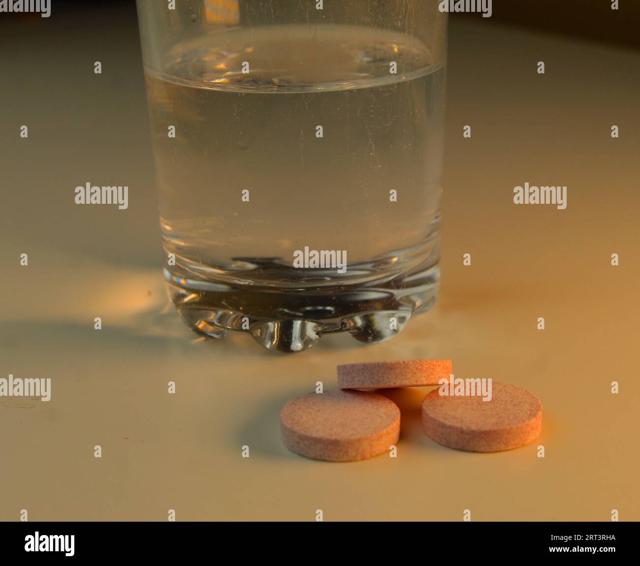 A photo of a couple of electrolyte tablets beside a glass of water ...