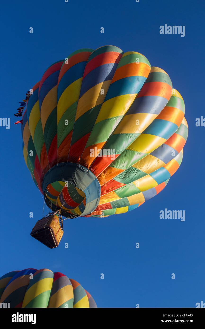 2 hot air balloons are rising in the early morning light into a blue ...