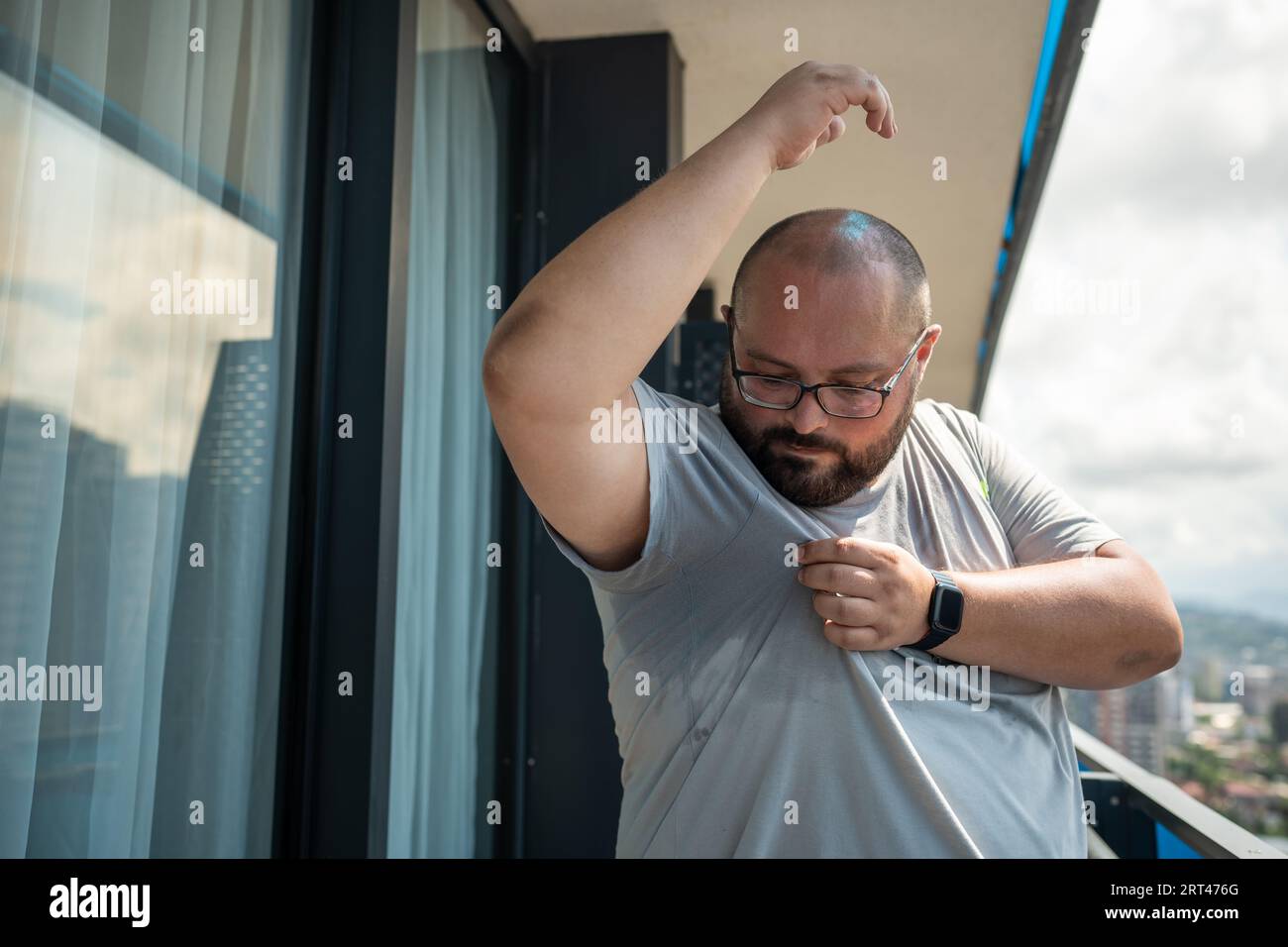 Overweight man suffering from heat, over sweating in summer standing on ...