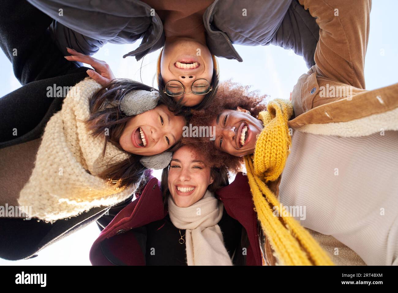 Low angle selfie of group of friends hugging in circle looking at ...