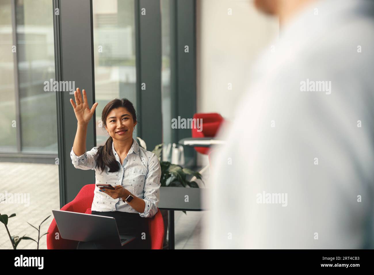 Female office worker waving Hi to her colleague during working day in ...