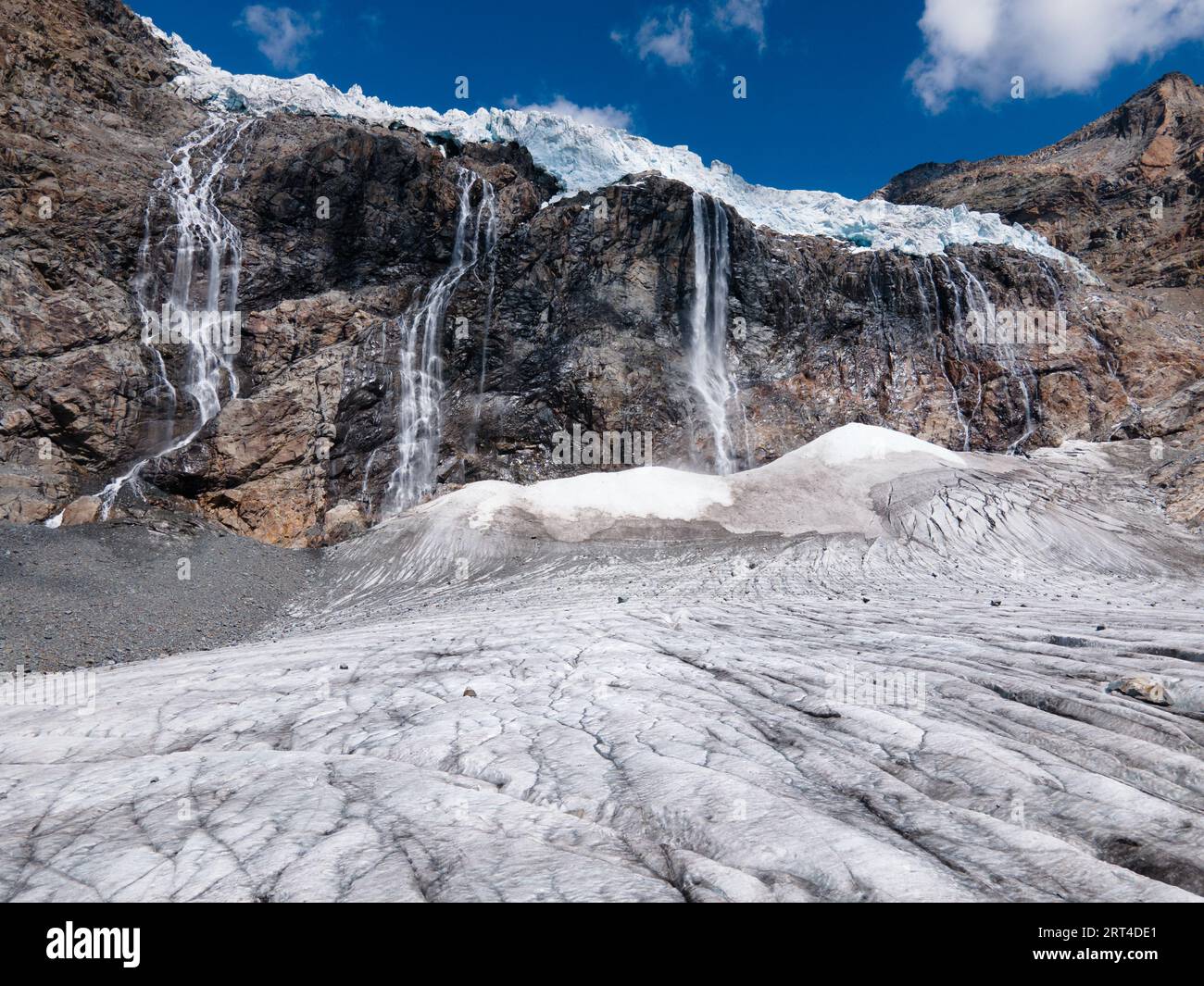 Aerial of melting glacier in the mountain, waterfall, lake, ice crevasses. Fellaria Glacier ...