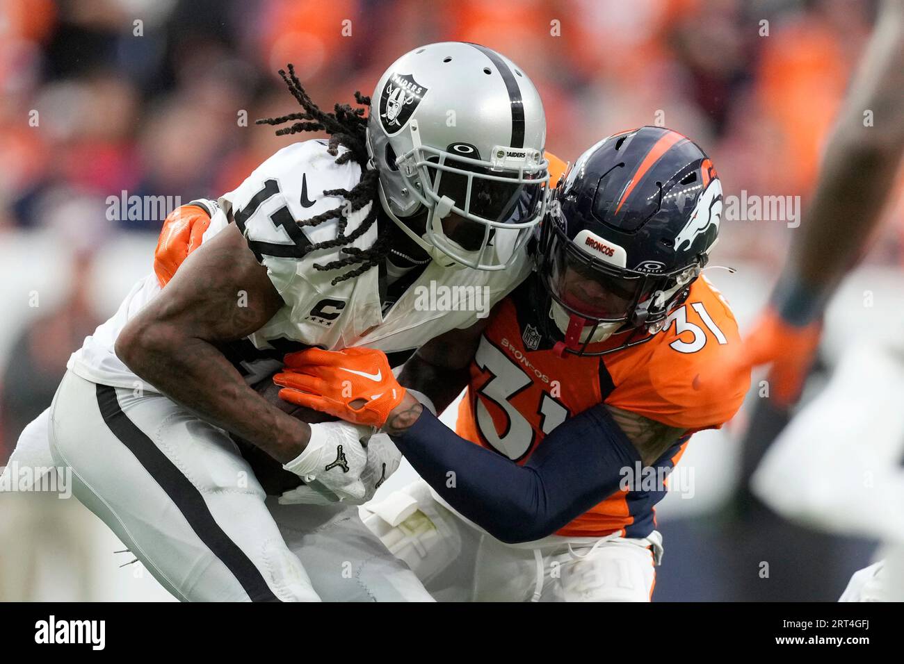 Las Vegas Raiders wide receiver Davante Adams (17) gets tackled by Denver Broncos safety Justin ...