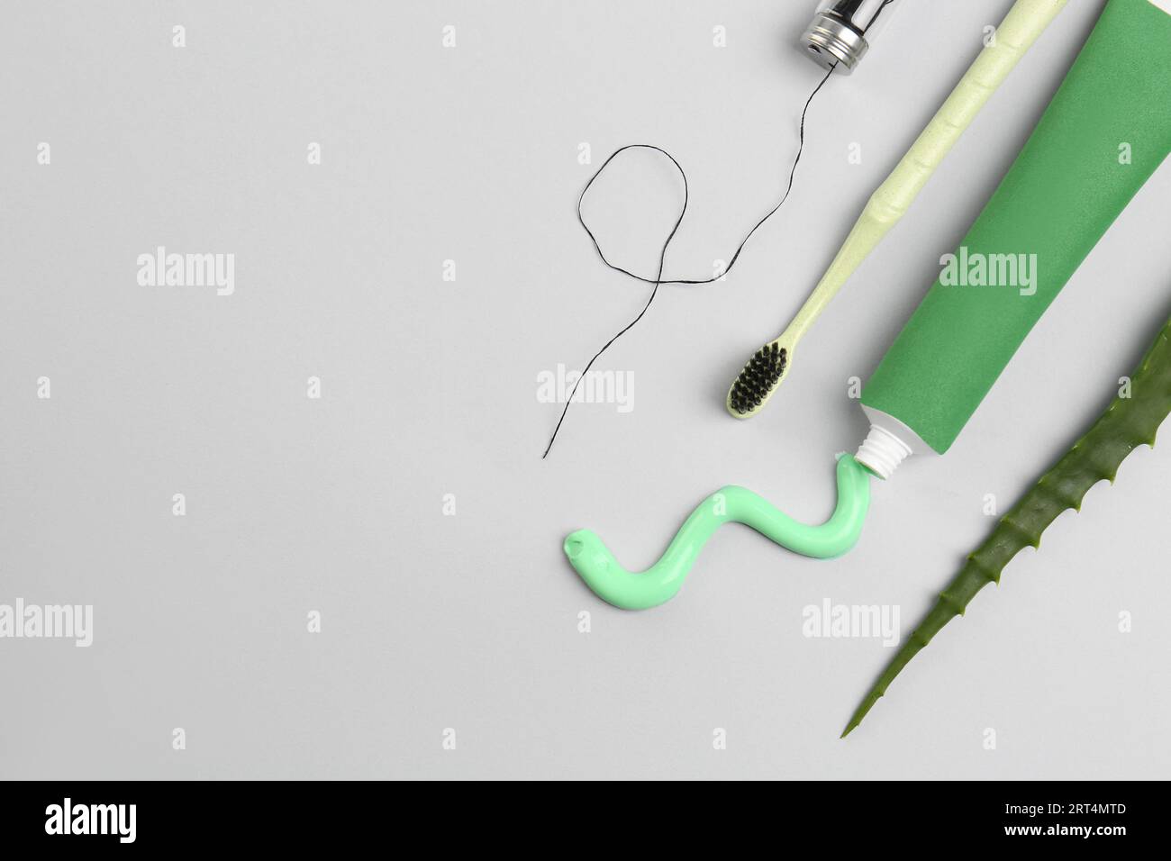 Tube of toothpaste, toothbrush, dental floss and fresh aloe on light ...