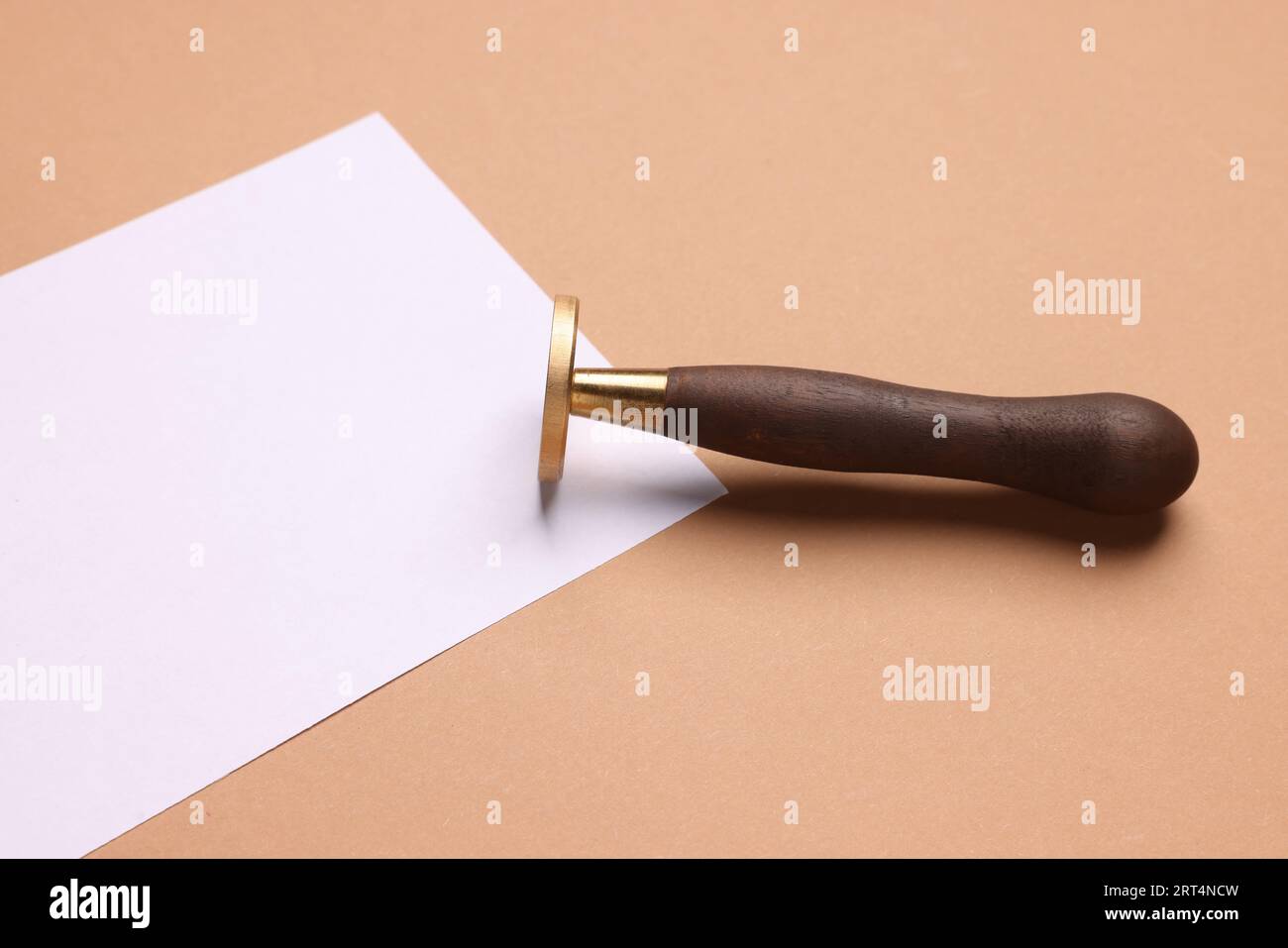 One stamp tool and sheet of paper on light brown background Stock Photo ...