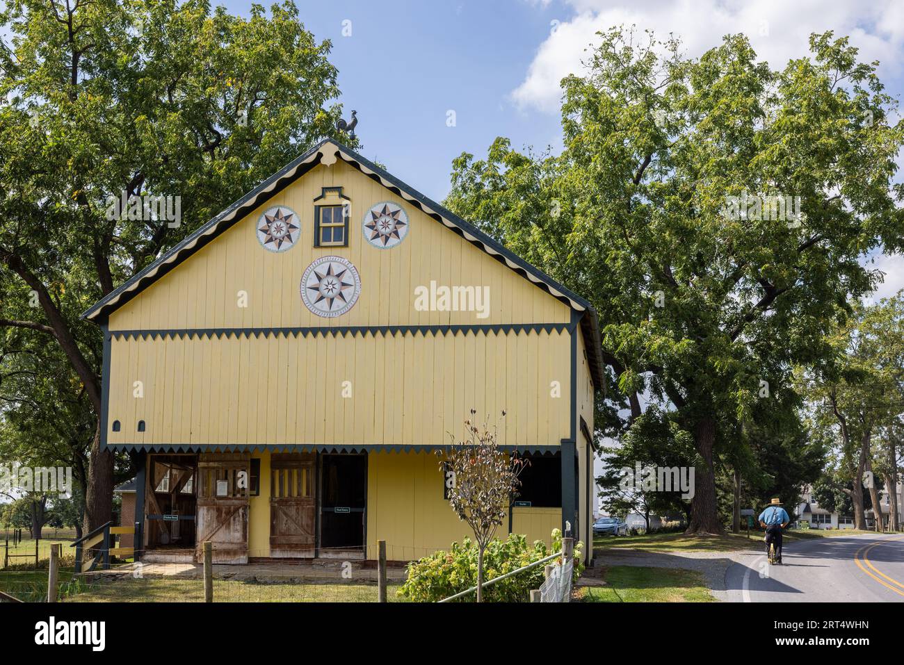 Yellow barn with hex signs and Amish man riding bicycle at Mascot ...