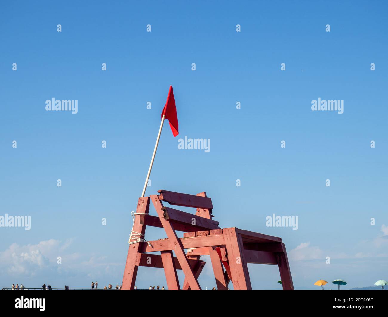 Red flag on a wooden platform. Flag as a symbol of danger. Bathing is ...