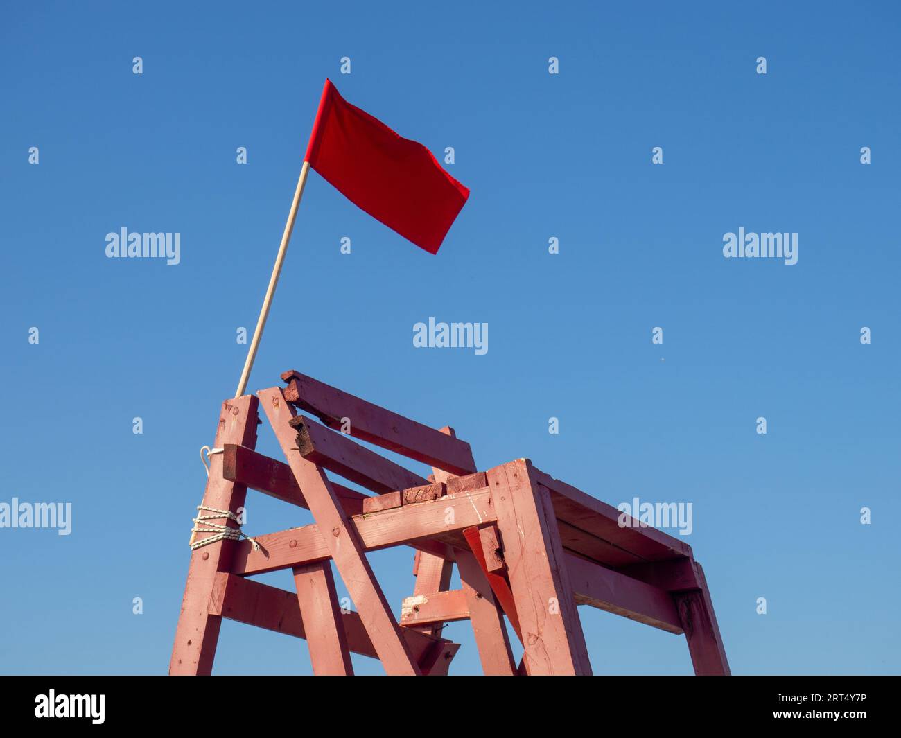 Red flag on a wooden platform. Flag as a symbol of danger. Bathing is ...
