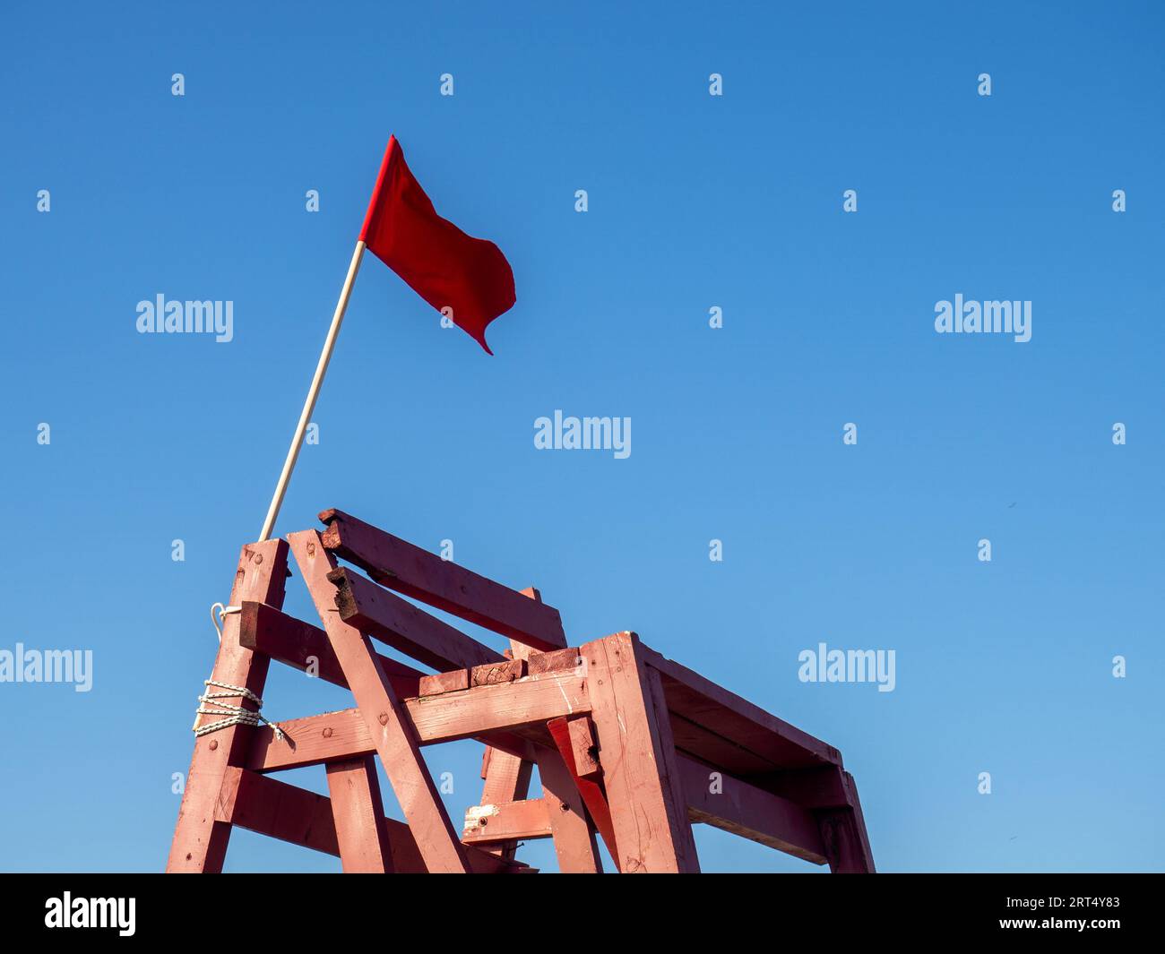 Red flag on a wooden platform. Flag as a symbol of danger. Bathing is ...