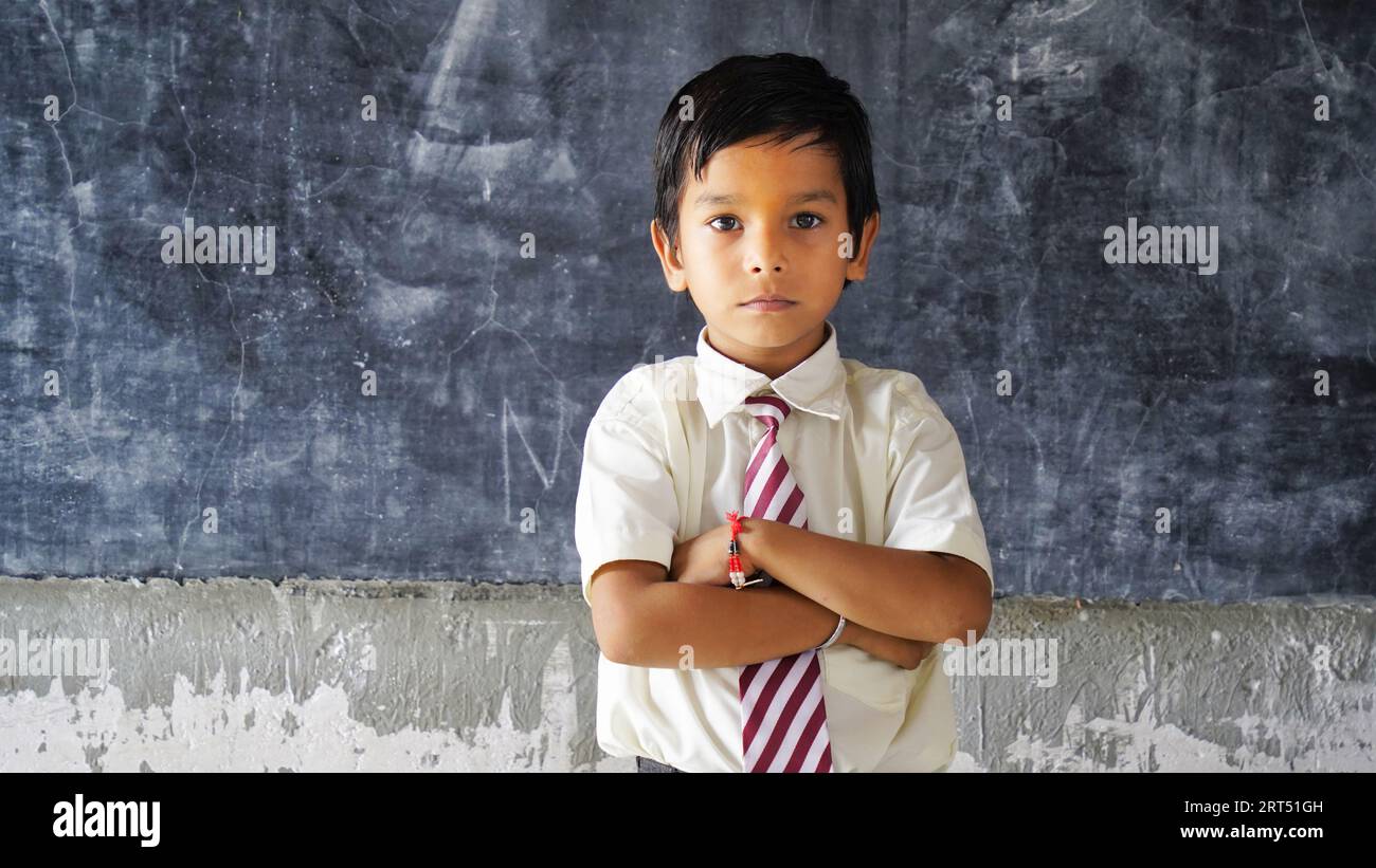 Indian school boy standing against blank chalkboard, intelligent and ...