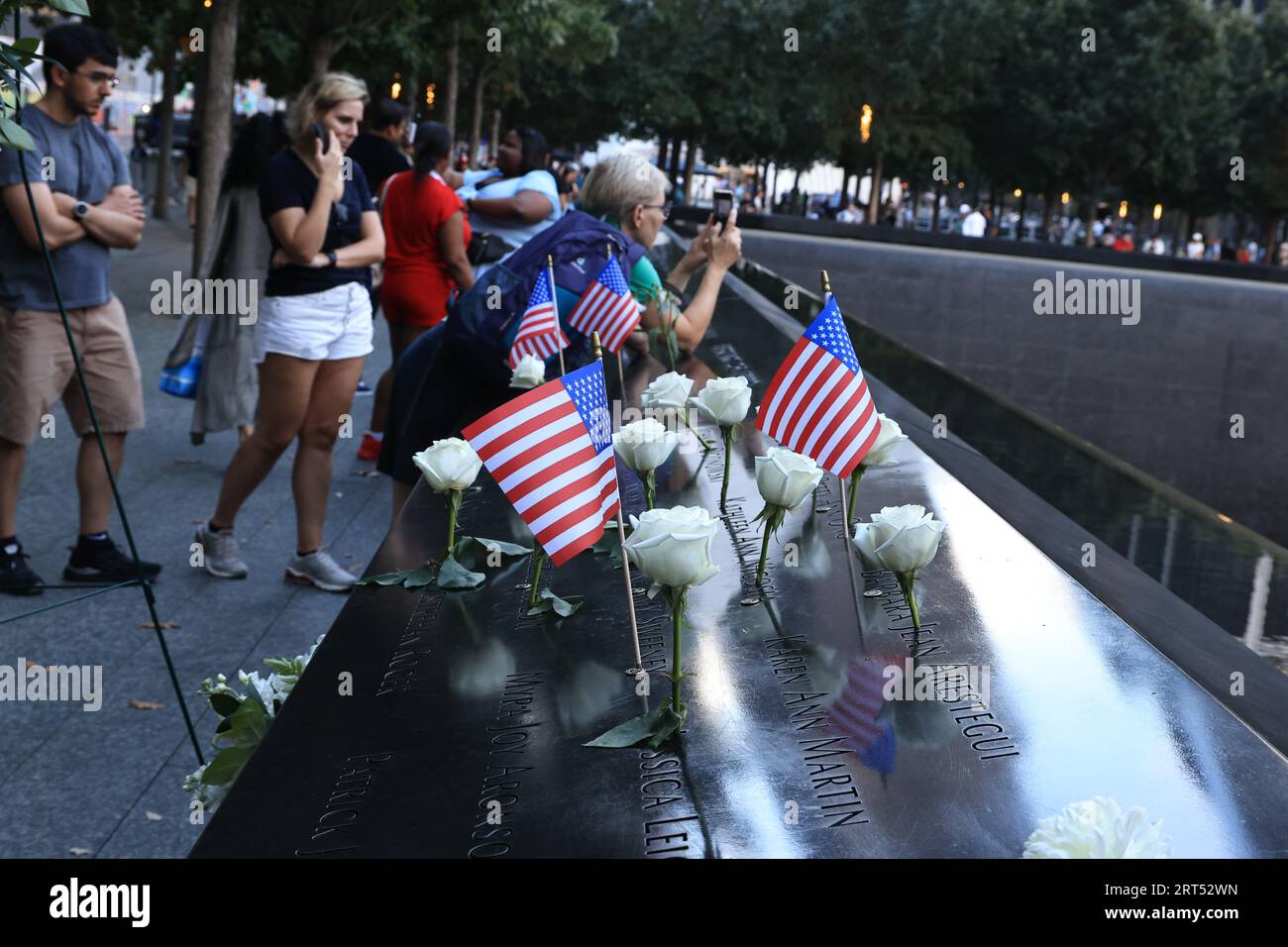 Flowers and US flags are laid on one of the North Pool panels at World ...