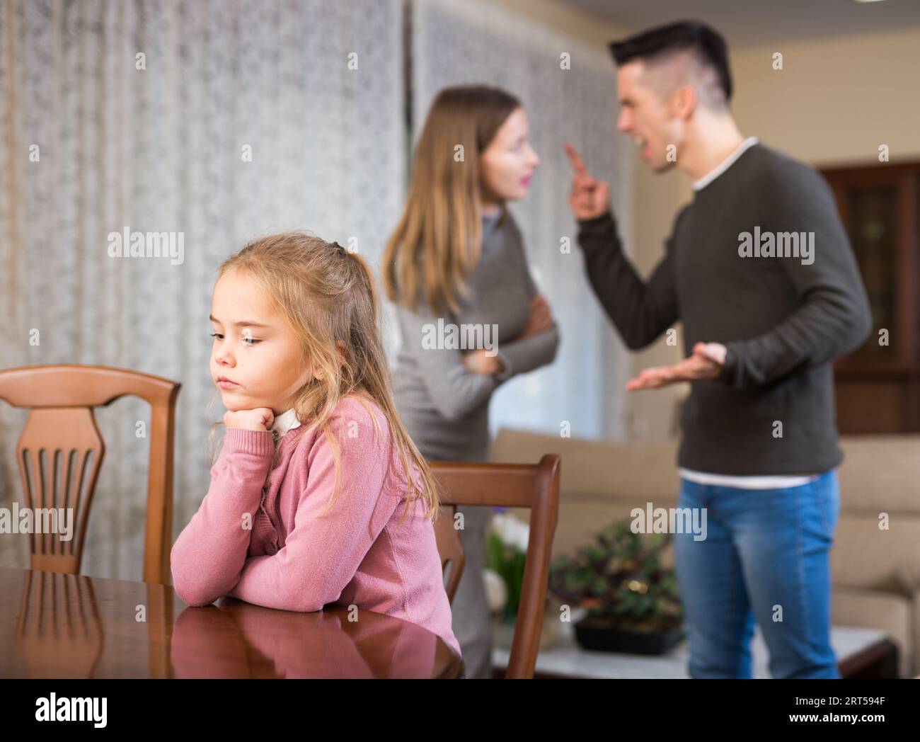 Upset tween girl while mom and dad arguing Stock Photo - Alamy