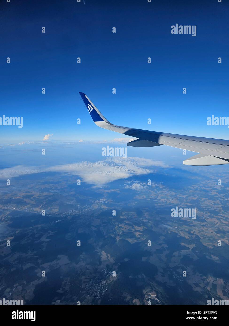 A passenger plane soaring high above a vast open space with clouds ...