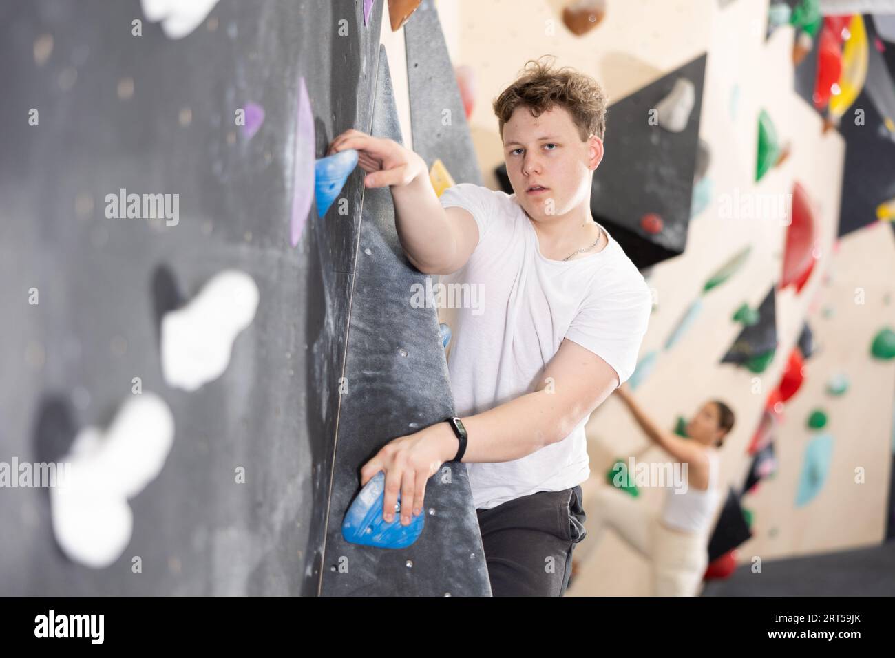 Teenage boy climbs steep artificial wall in sports complex and trains ...