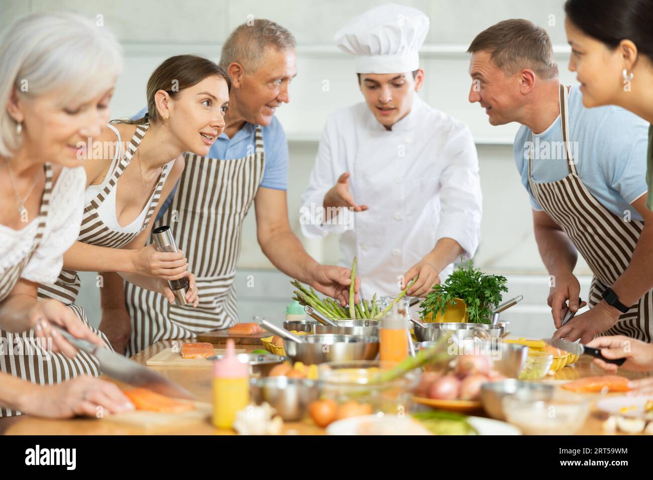 Chef in uniform teaches cooking class students how to clean and cut ...