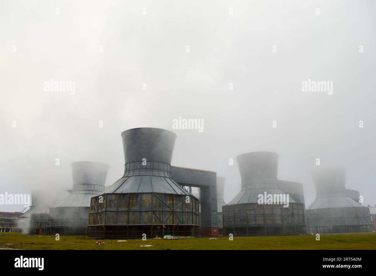 Large cooling towers in water and fog at an oil refinery, petrochemical ...