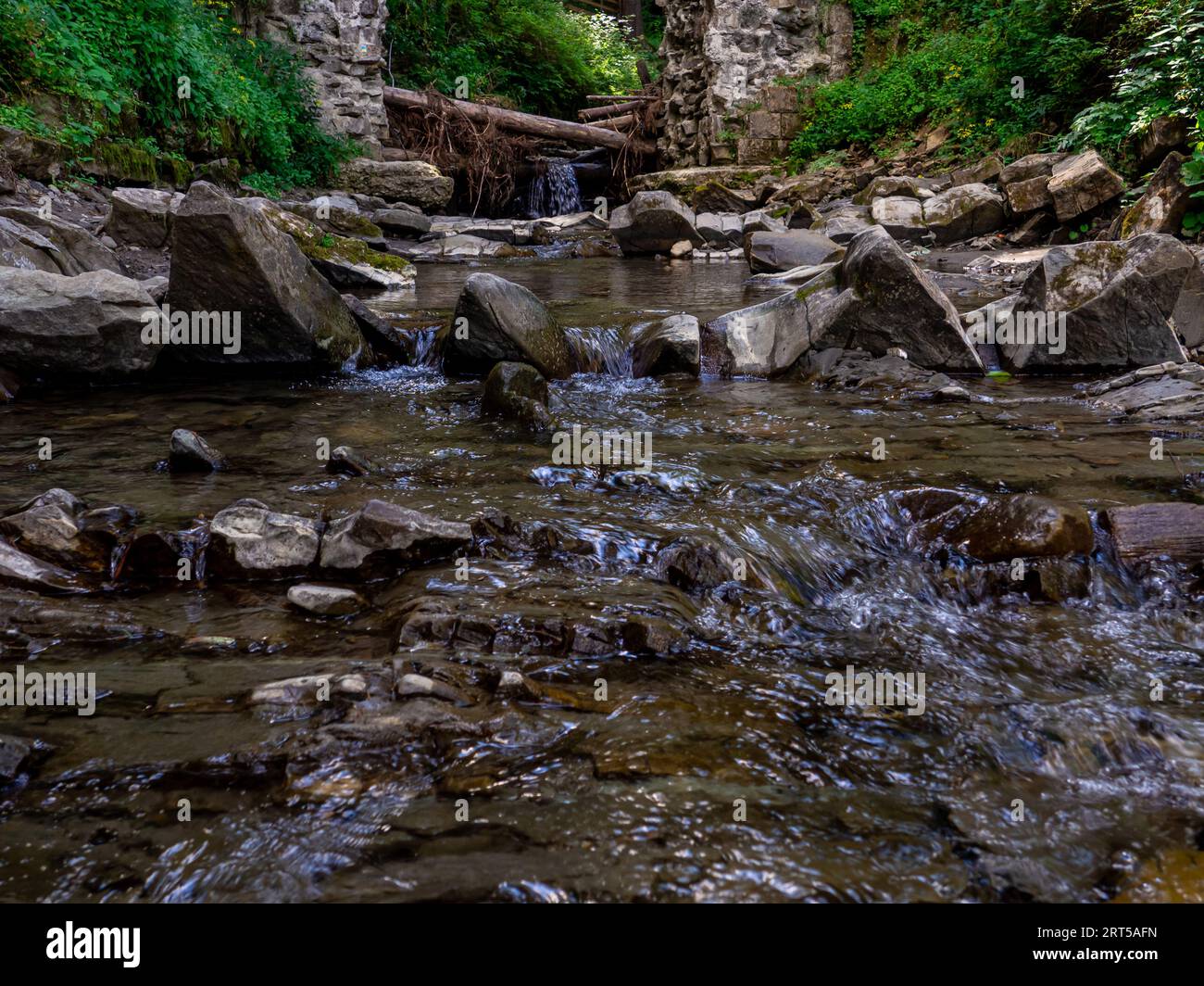 Small river flowing rapidly and vividly through its wild stony valley ...
