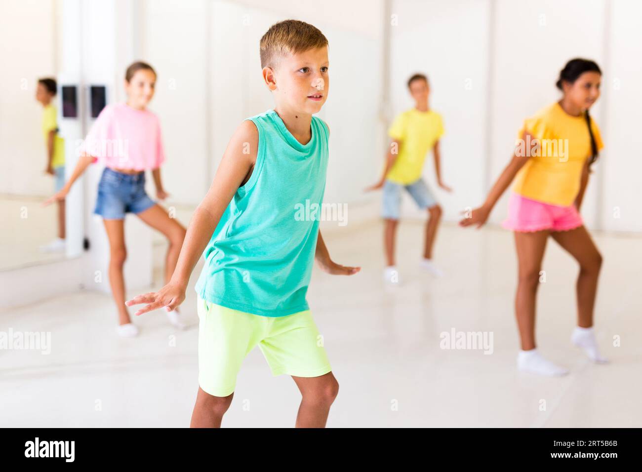 Concentrated tween boy learning charleston during group dance class ...