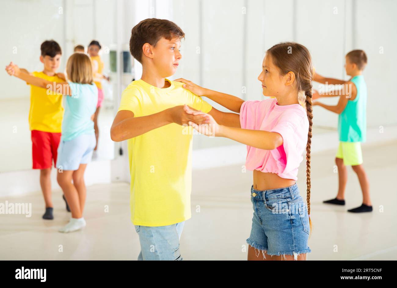 Tween boy and girl practicing slow pair dancing during group class ...