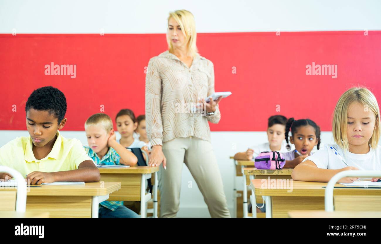 Teacher controlling learning process in primary school Stock Photo - Alamy