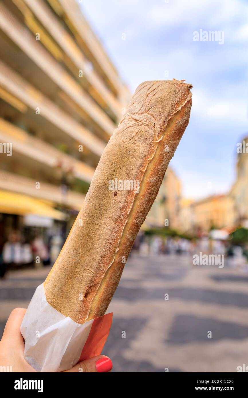 Woman s hand holding a freshly baked rustic French baguette bread from ...