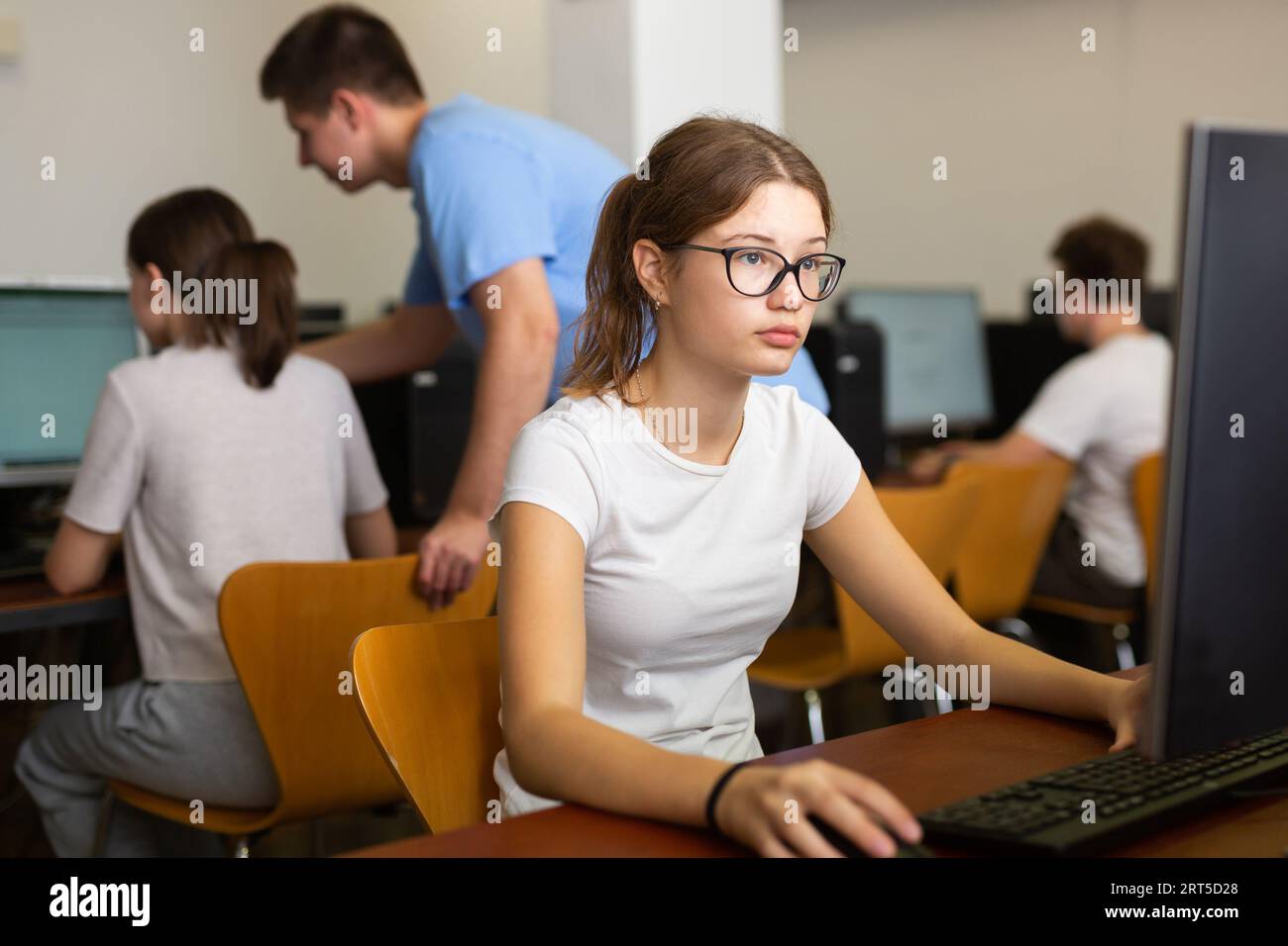 Interested teen girl studying with classmates in school class Stock ...