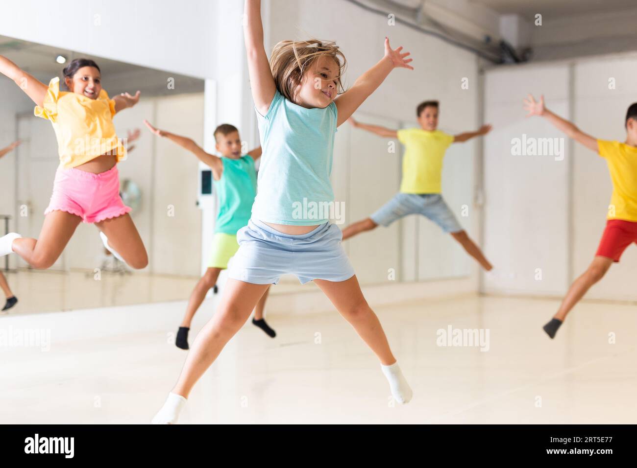 Children jumping while studying modern style dance in class indoors ...