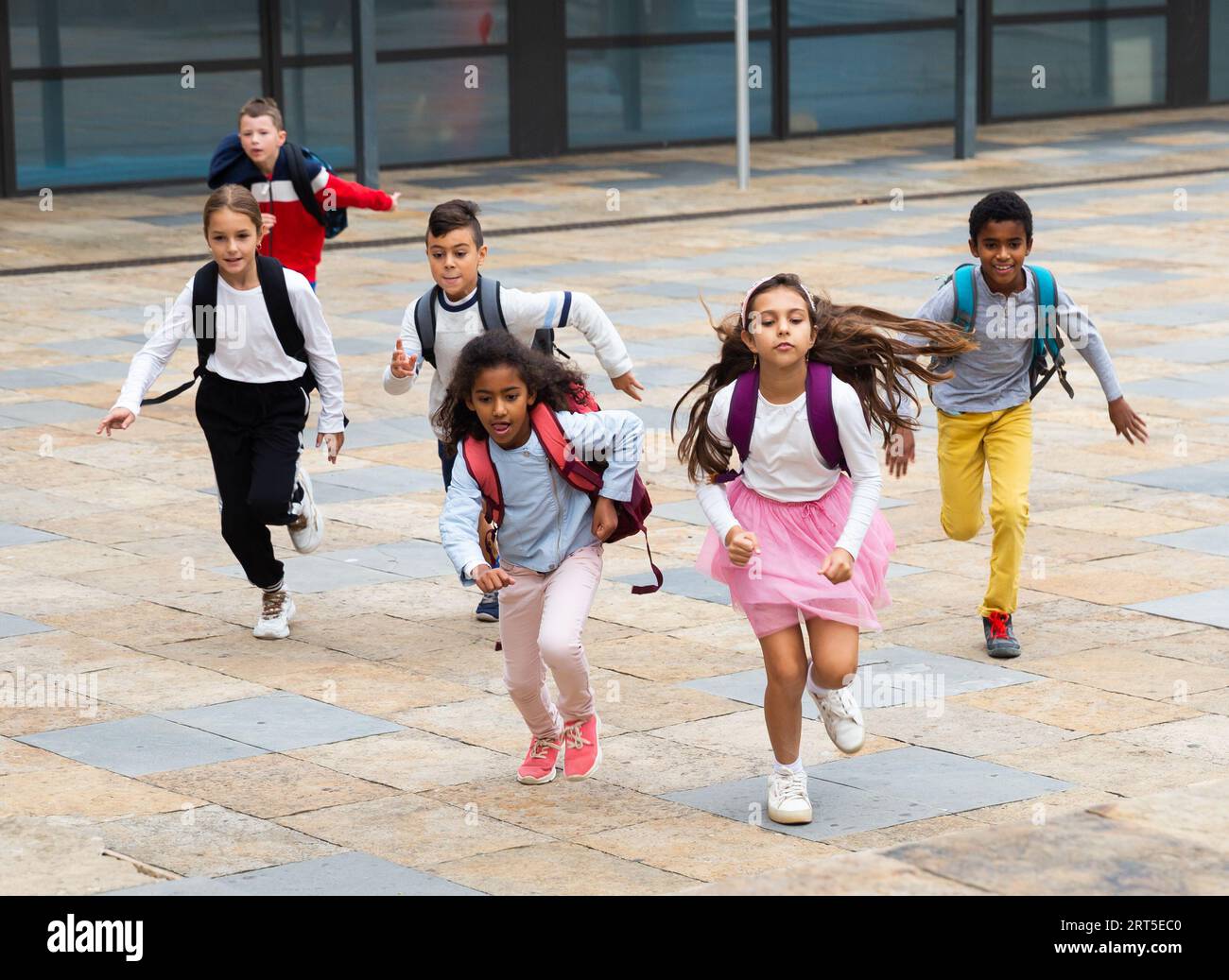 Happy tween schoolchildren with backpacks running to school outdoors ...