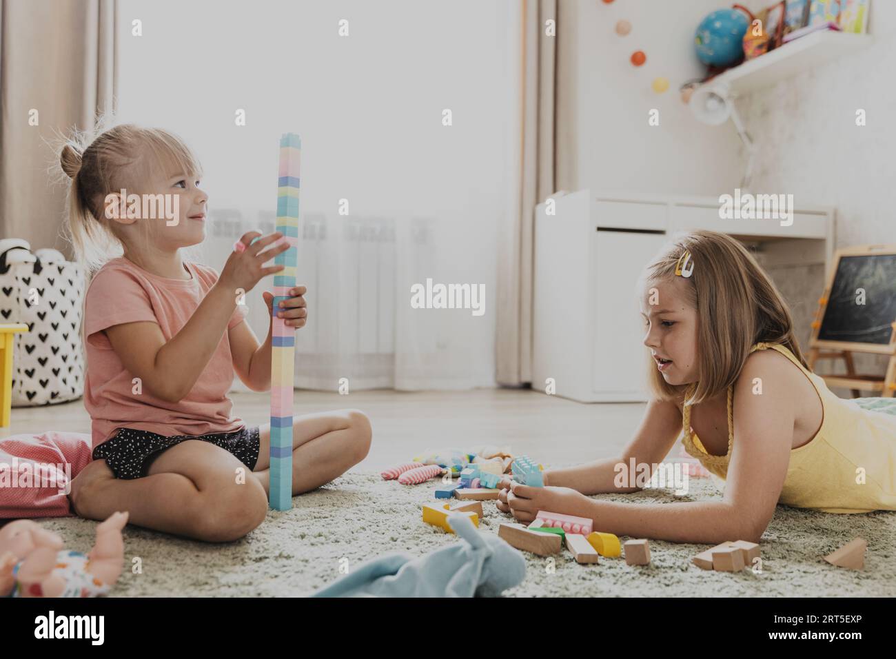 Children playing with colorful toys. Kids sitting on carpet at home ...