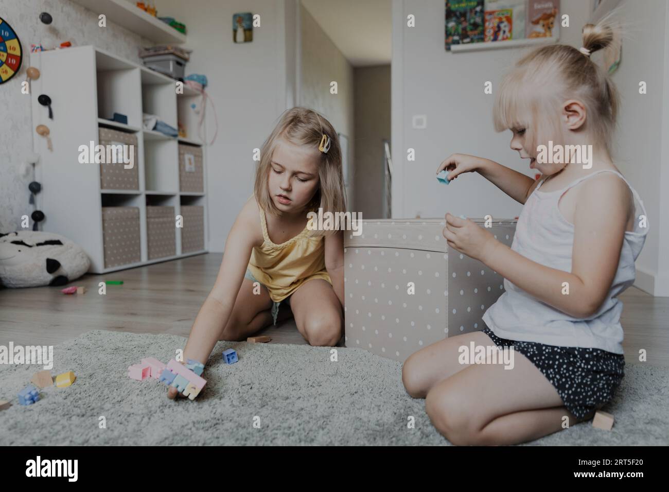 Children cleaning toys from floor after playing, collect them to ...