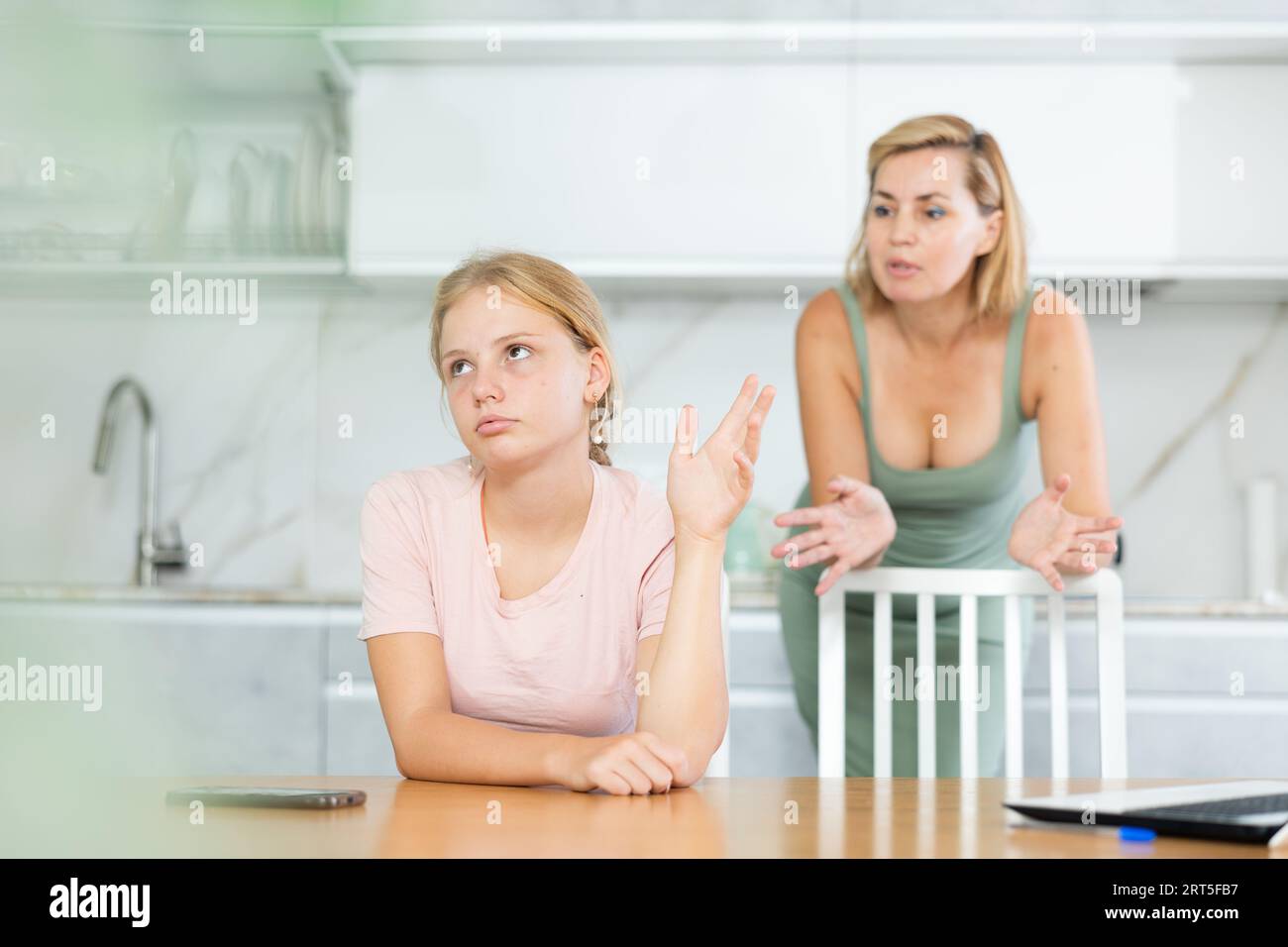 Frustrated teenage girl making dismissive gesture to disgruntled mother ...