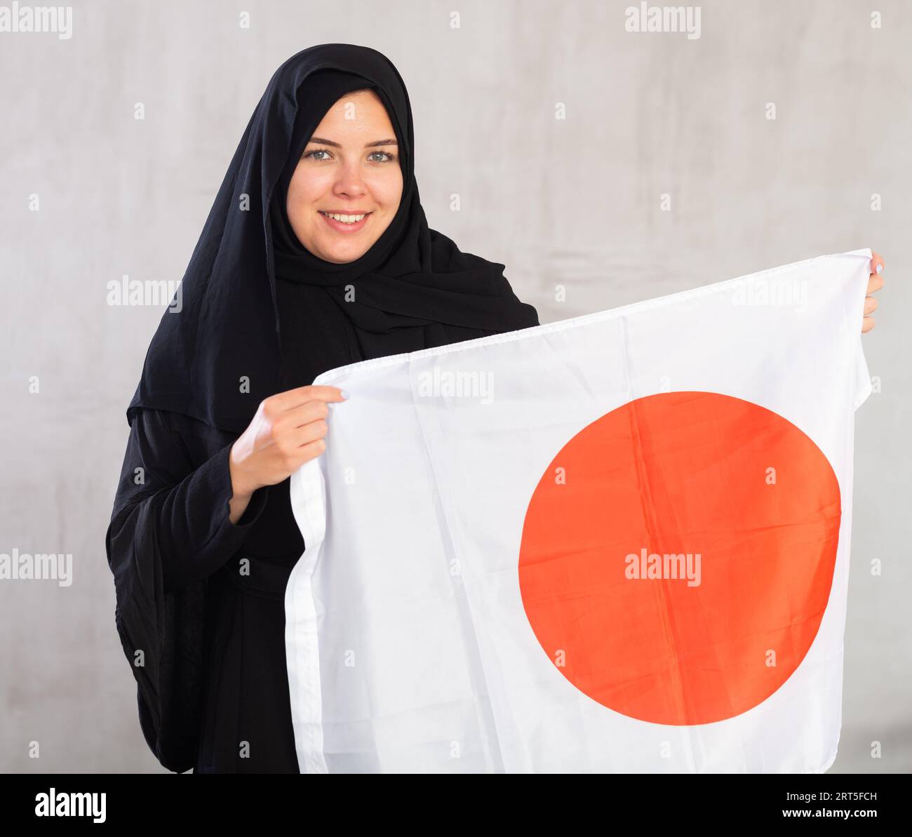 Smiling joyful Muslim woman in traditional black hijab holds flag of ...