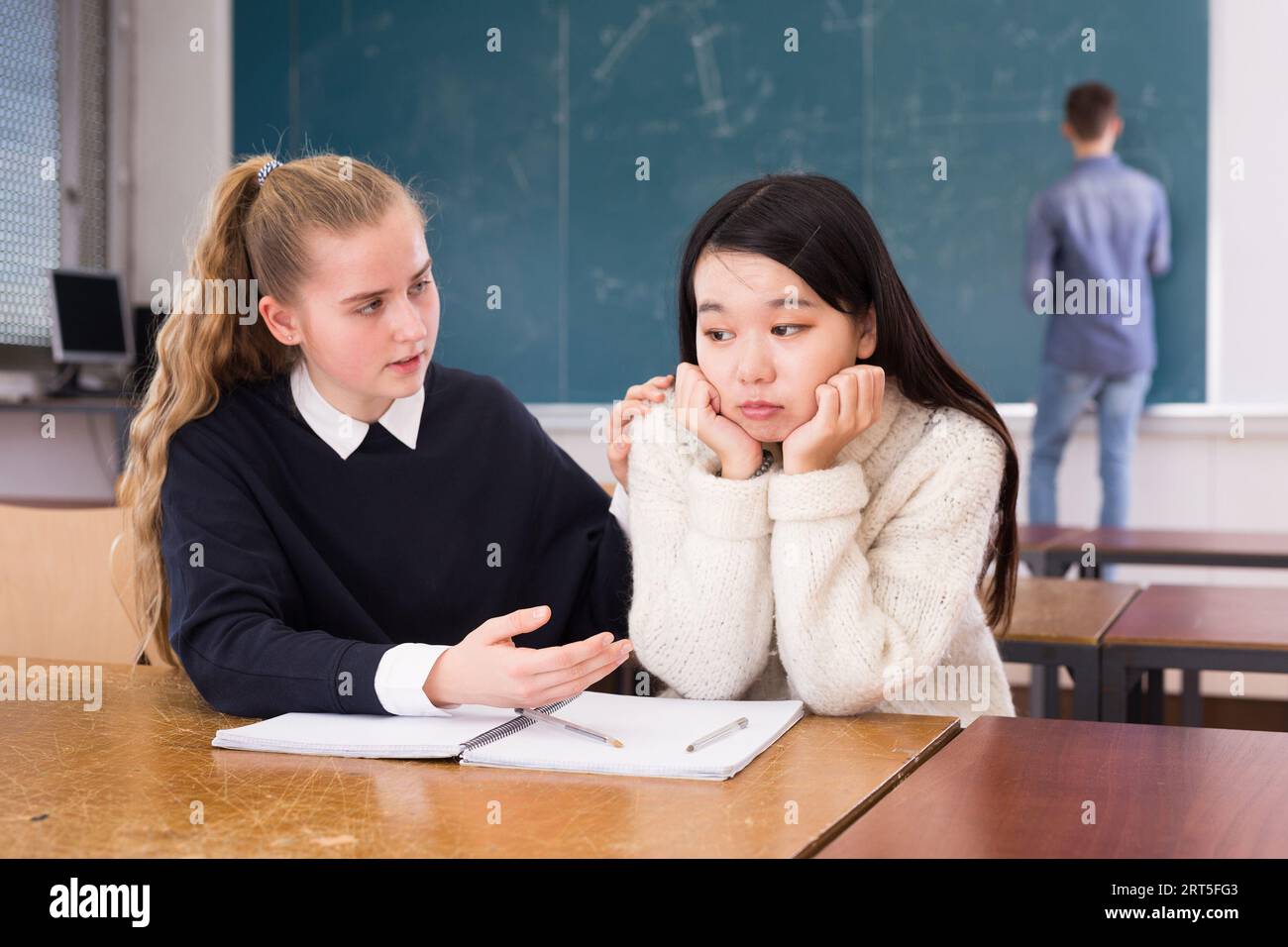 Teen female student supporting upset Chinese girl in classroom Stock ...
