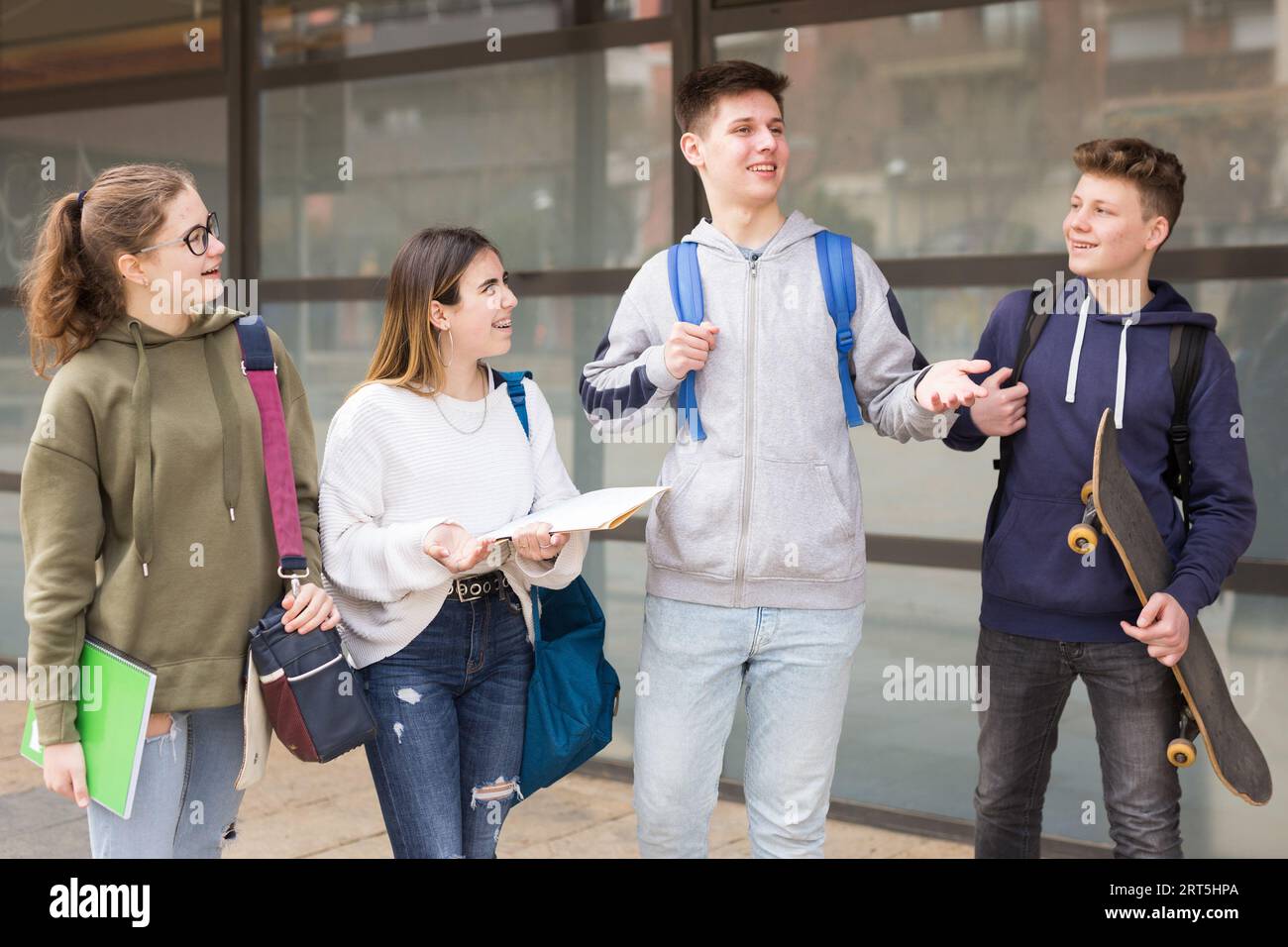 Four teenagers talking about play on walk in street Stock Photo - Alamy
