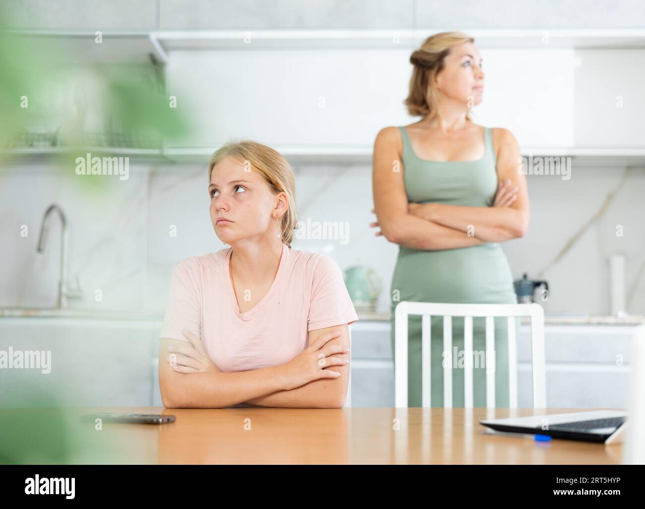 Blurry mum and girl crossed arms and standing apart from each other ...