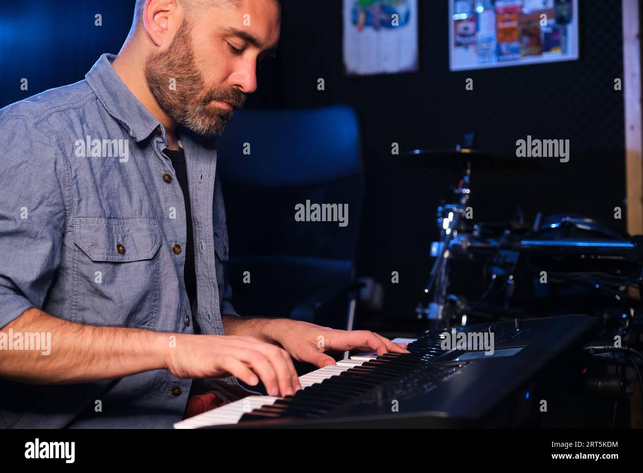 Musician man playing keyboard synthesizer piano in a recording studio ...