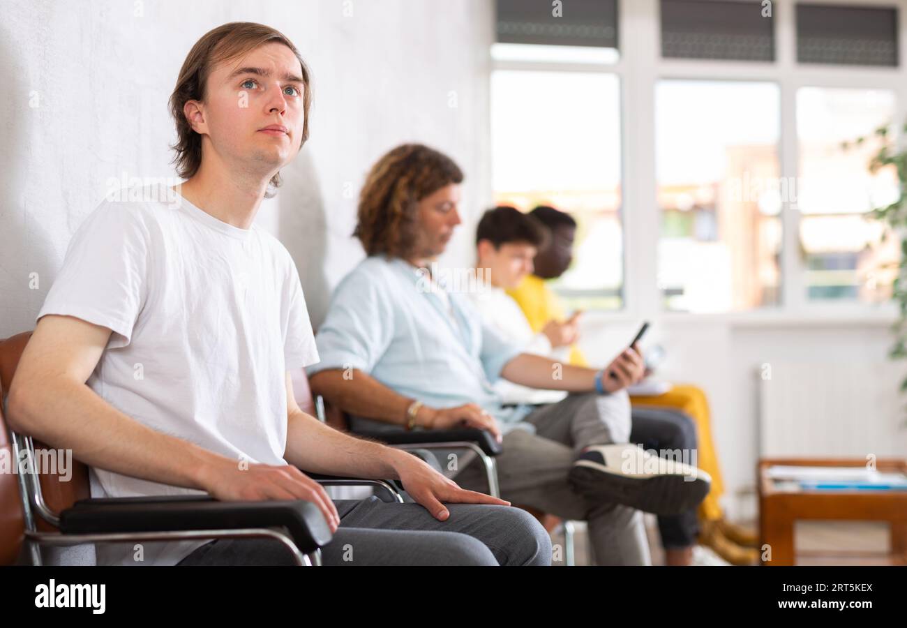 Portrait of a young man sitting waiting Stock Photo - Alamy