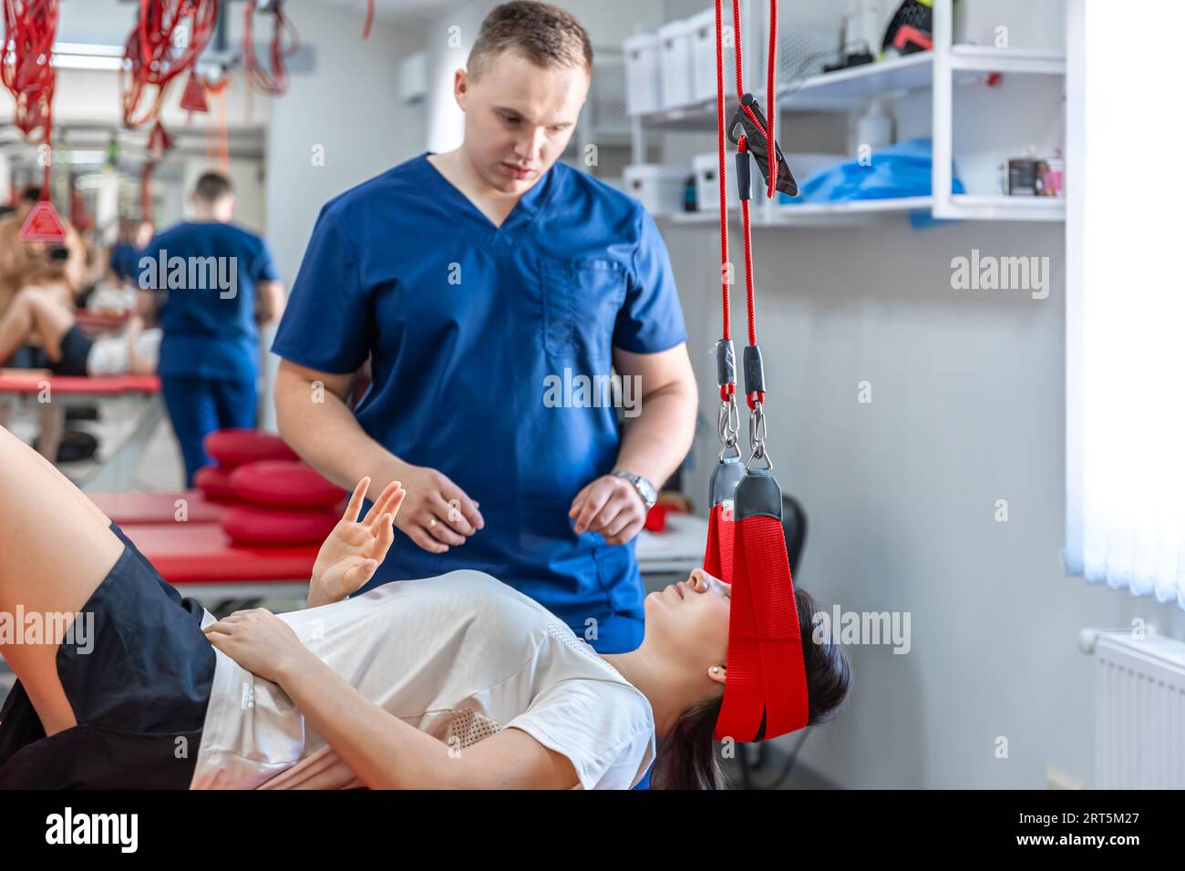 Female patient hanging on suspensions at rehabilitation center Stock ...