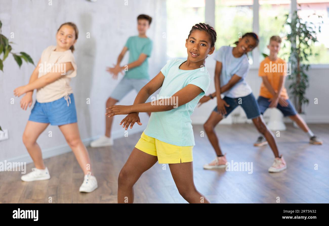 Positive juvenile girl engaged in Breakdancing in training room with ...